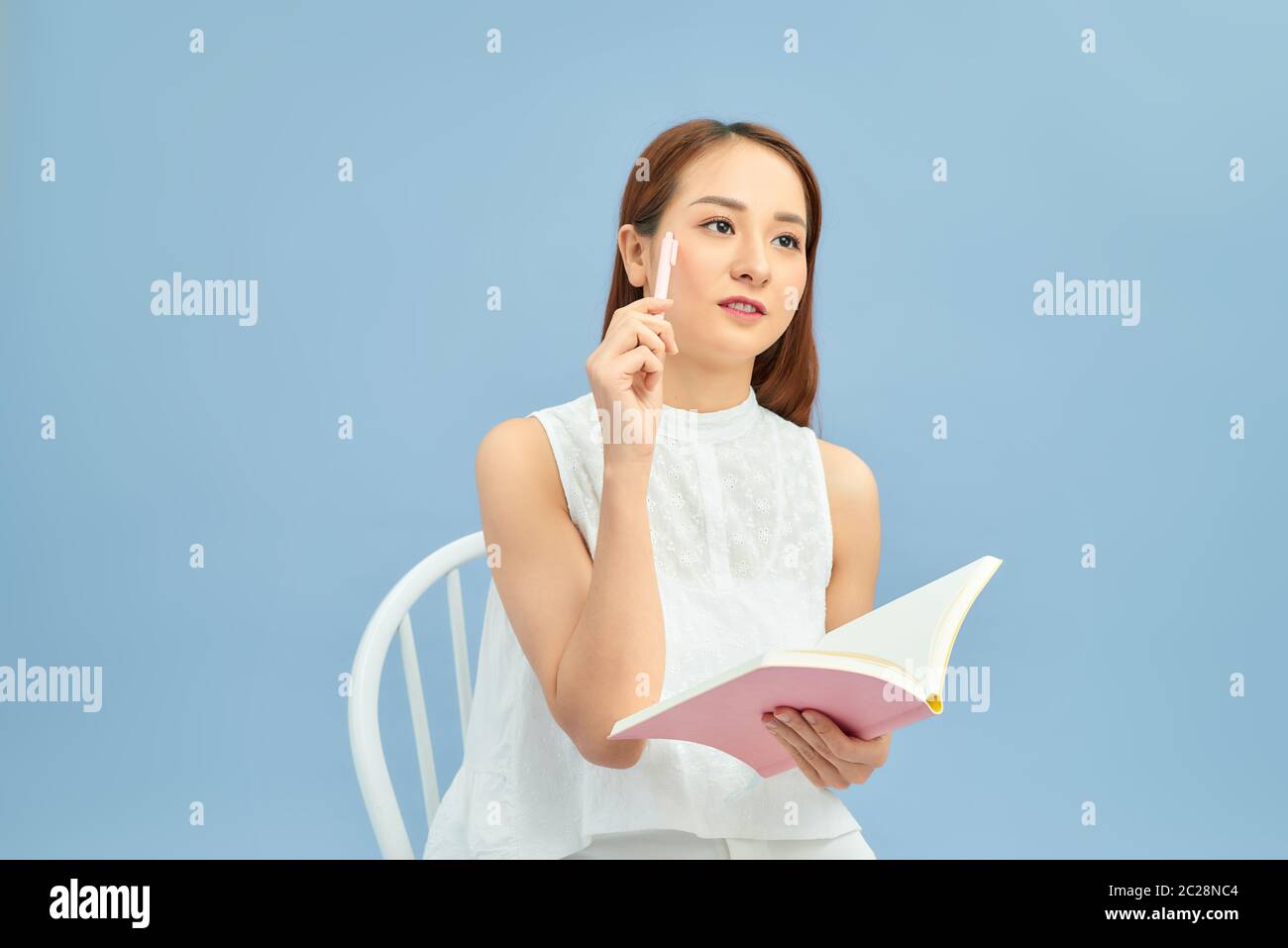 Smiling lovely girl writing in a diary while sitting on a chair Stock ...
