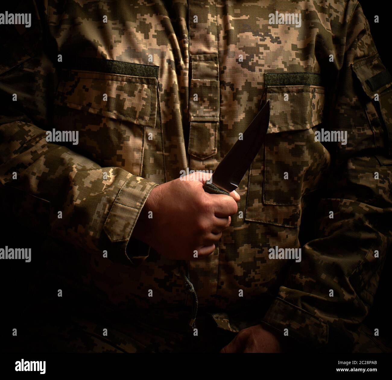 soldier dressed in military uniform holds a sharp tactical knife in his ...