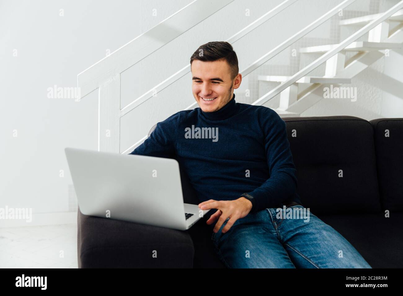 Happy handsome young man looking at laptop screen, working with it ...