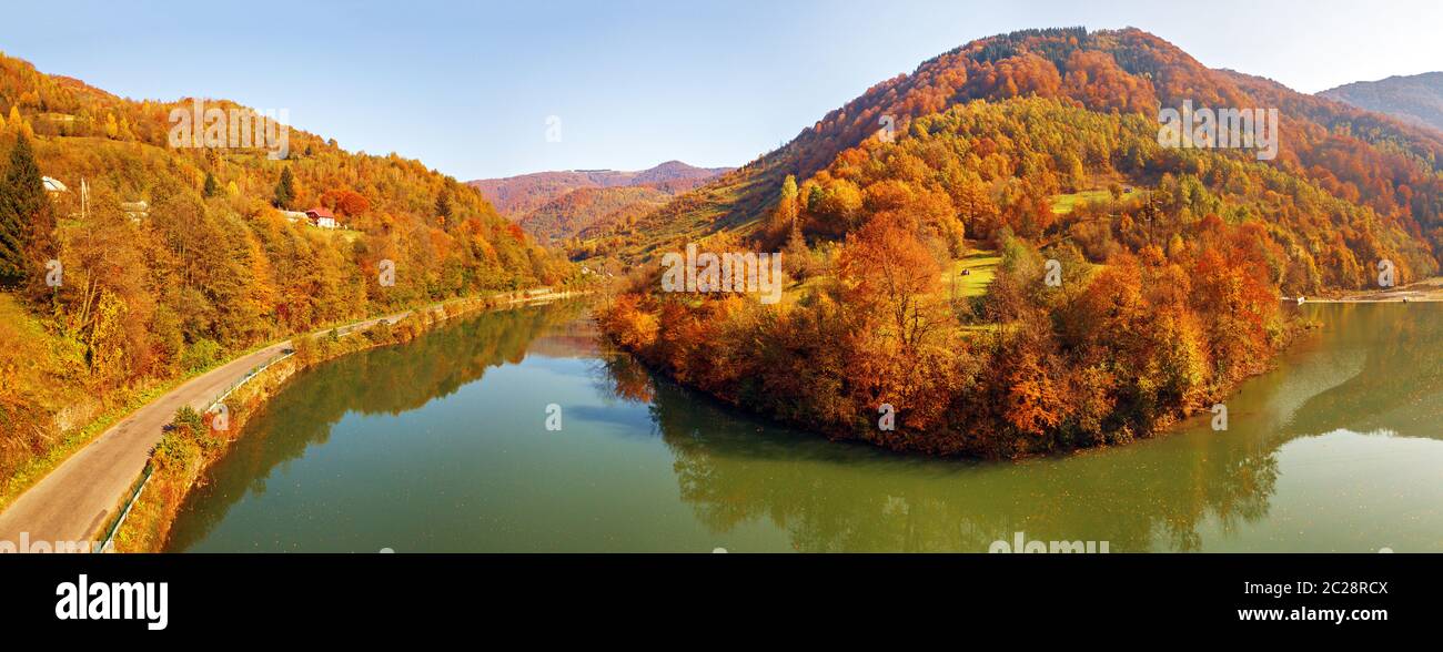Mountain river flows in autumn colored valley. Panorama of road and ...