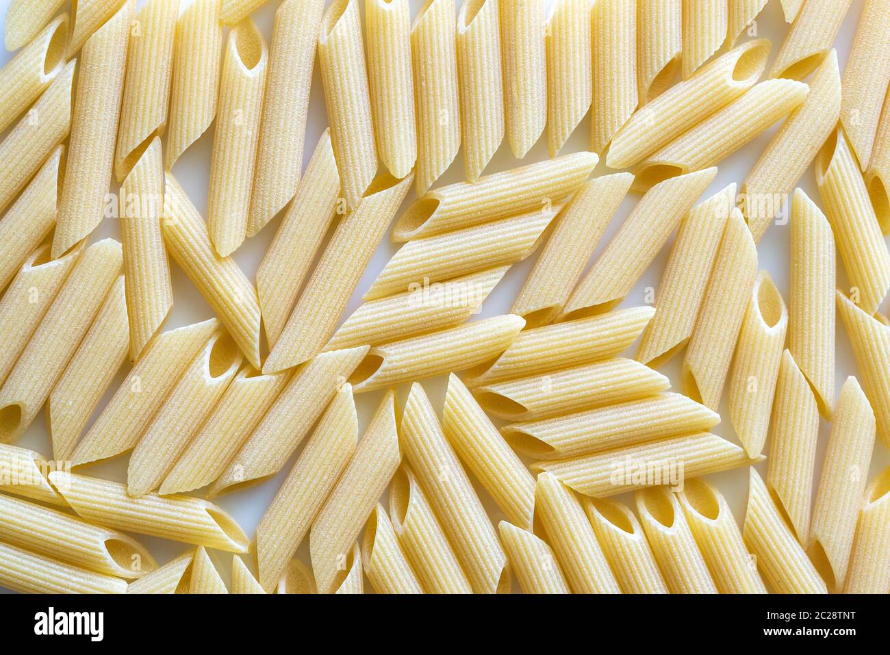 Raw penne pasta on the white background: top view Stock Photo - Alamy