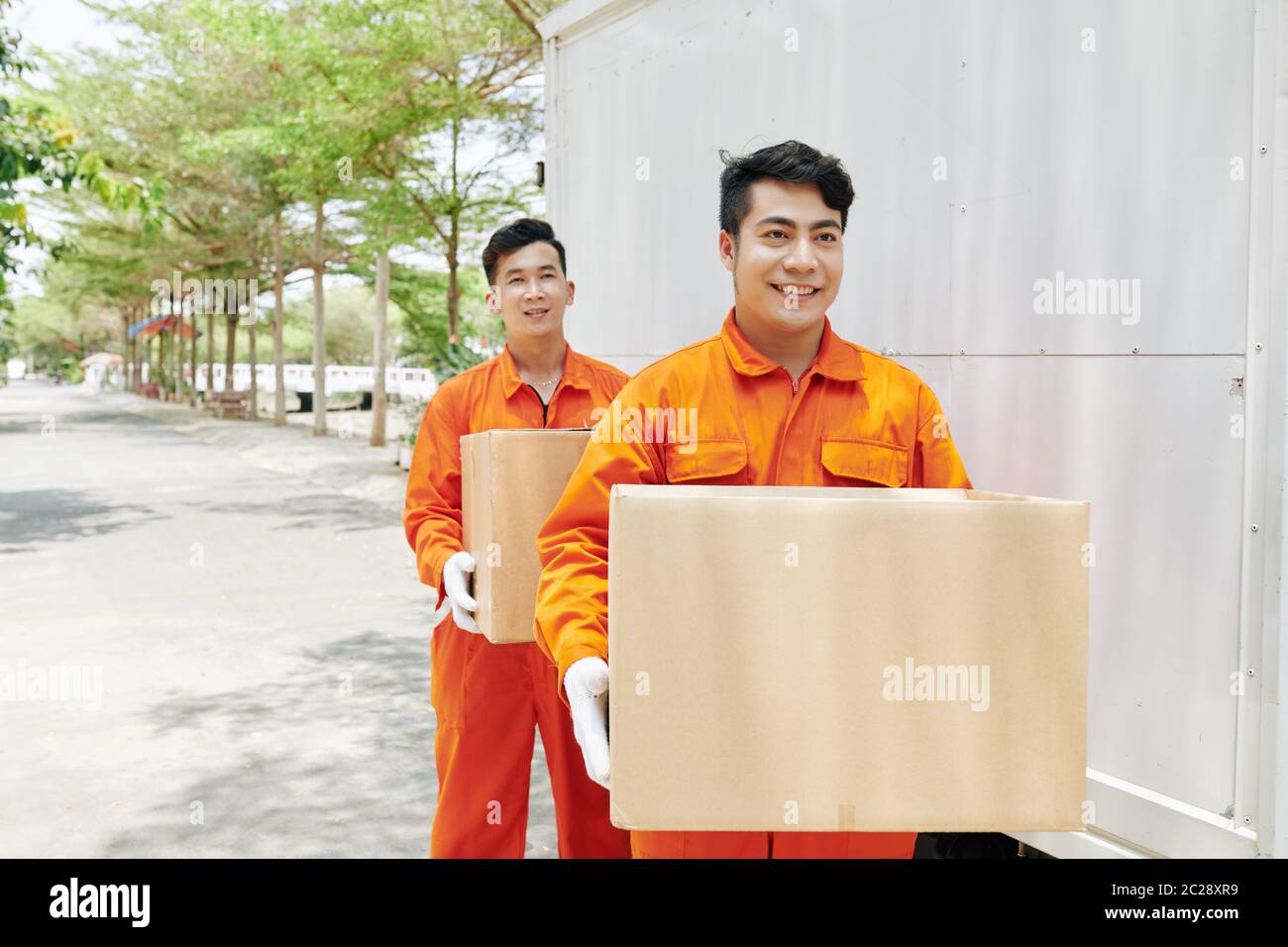 Joyful delivery service workers wearing orange uniform clothes and ...
