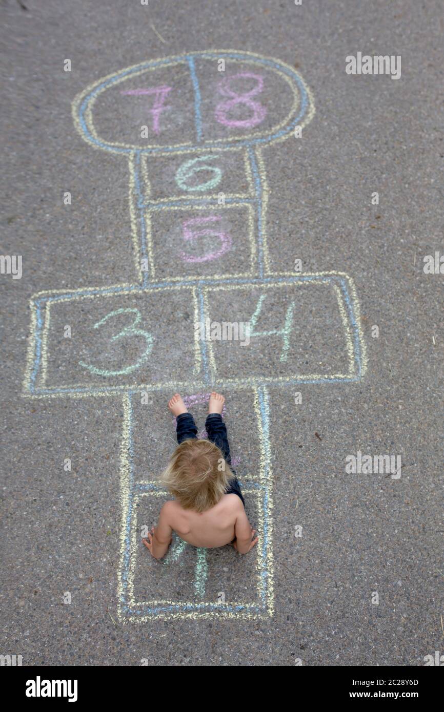 Child, blond boy, playing hopscotch on the street, summertime Stock ...
