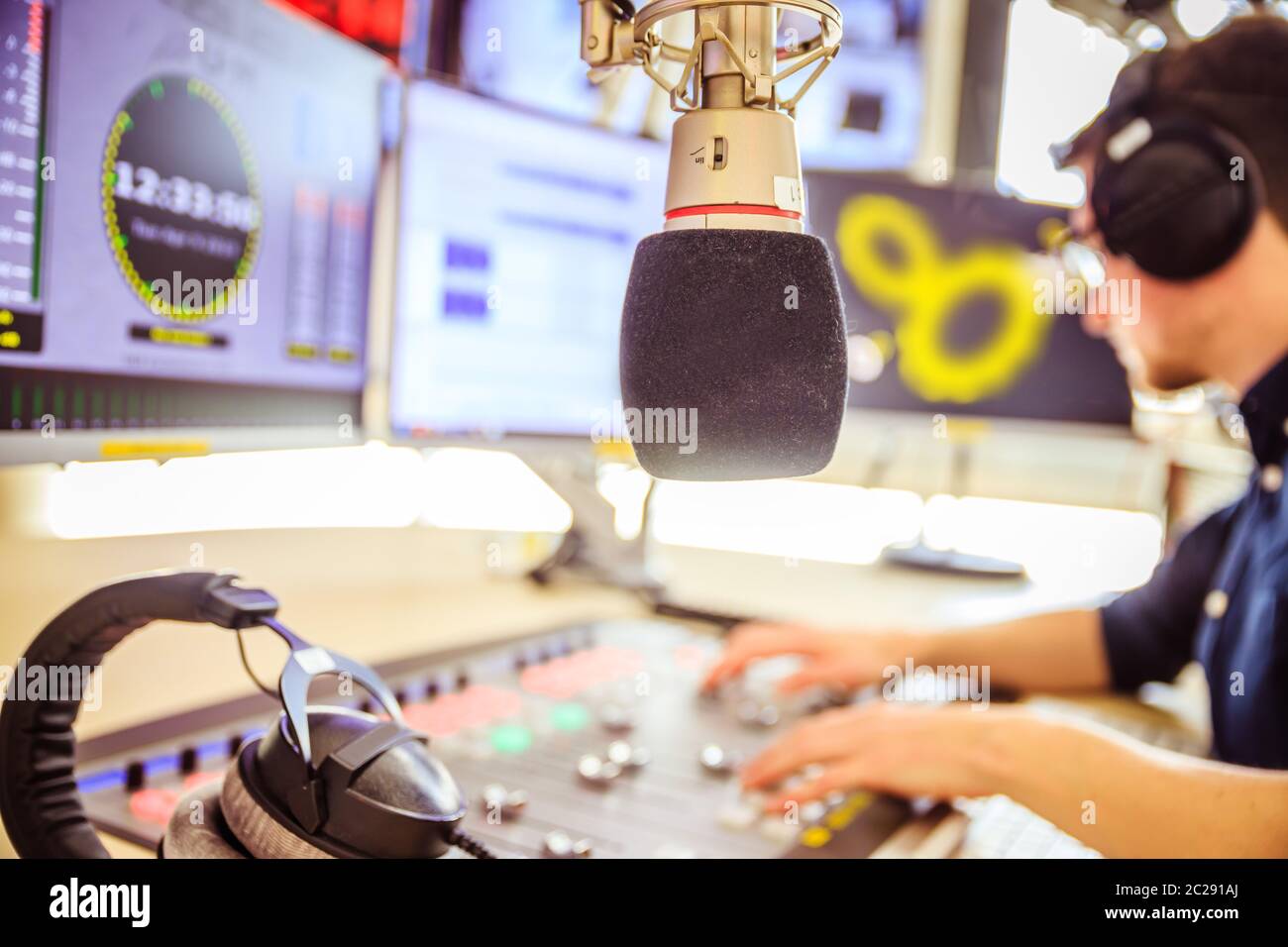 Radio moderator is sitting in a modern broadcasting studio and talking ...