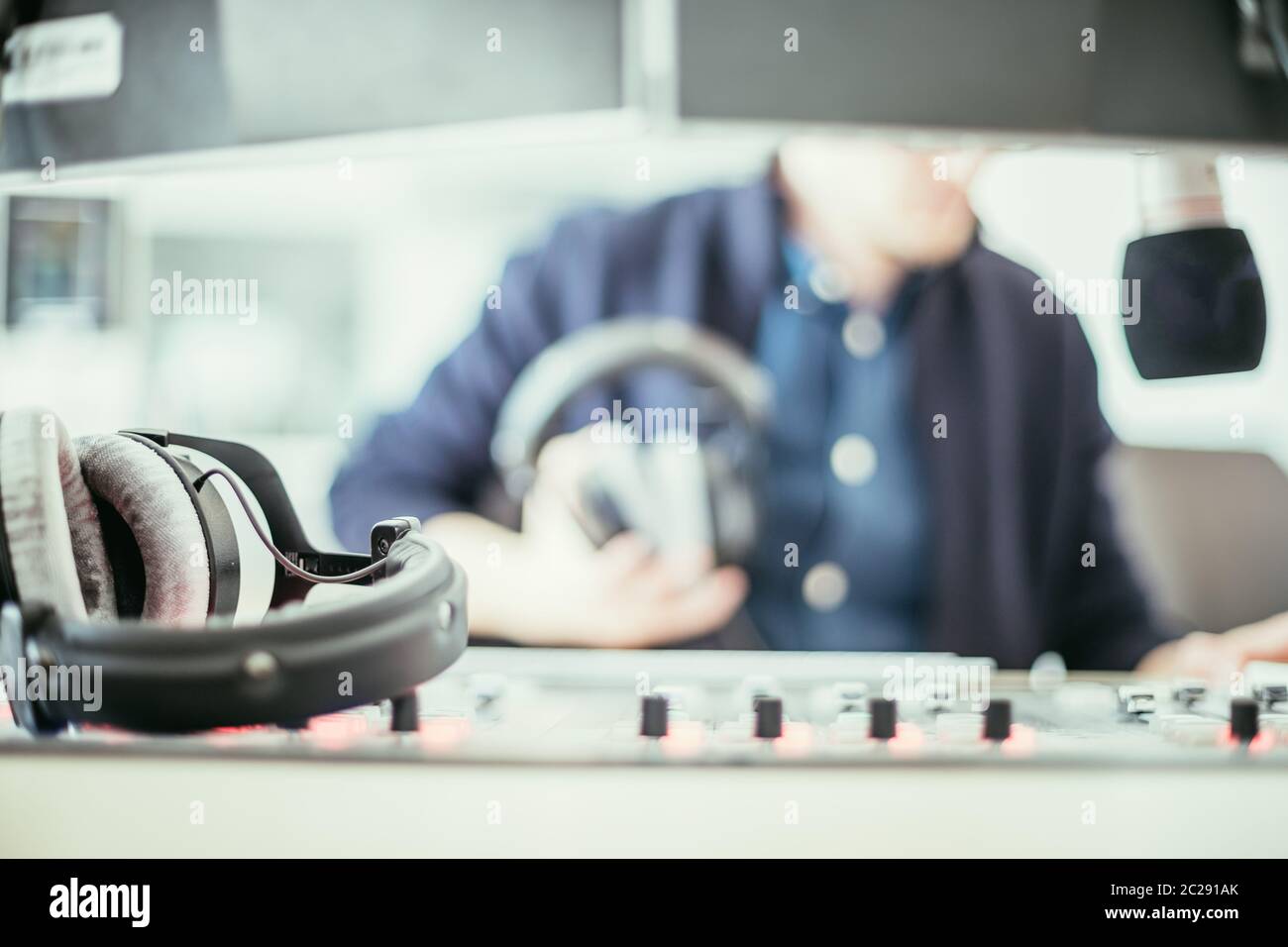 Radio moderator is sitting in a modern broadcasting studio and talking ...