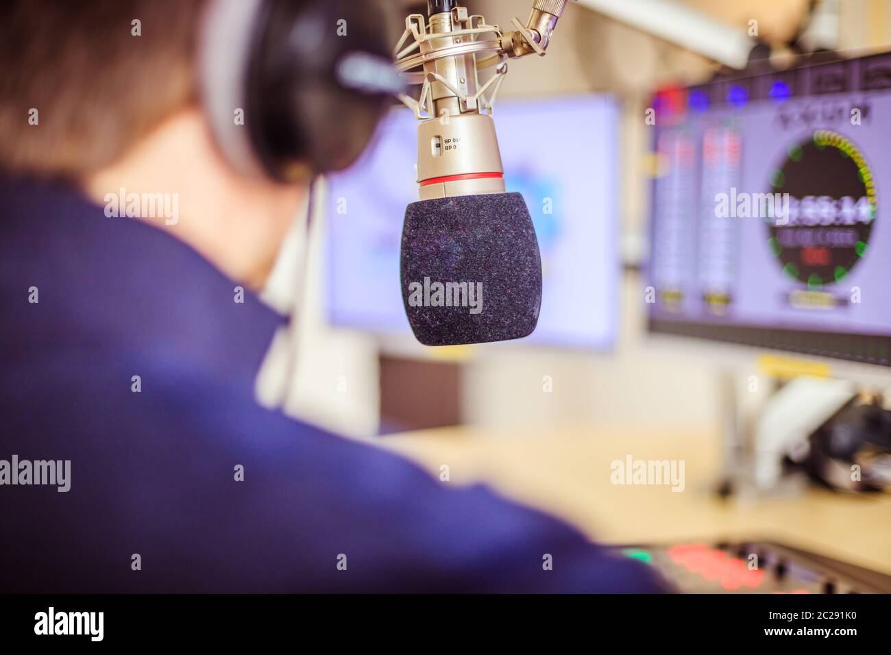 Radio moderator is sitting in a modern broadcasting studio and talking ...