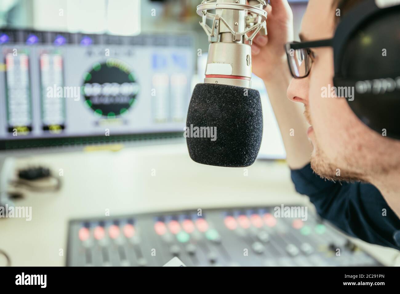 Radio moderator is sitting in a modern broadcasting studio and talking ...