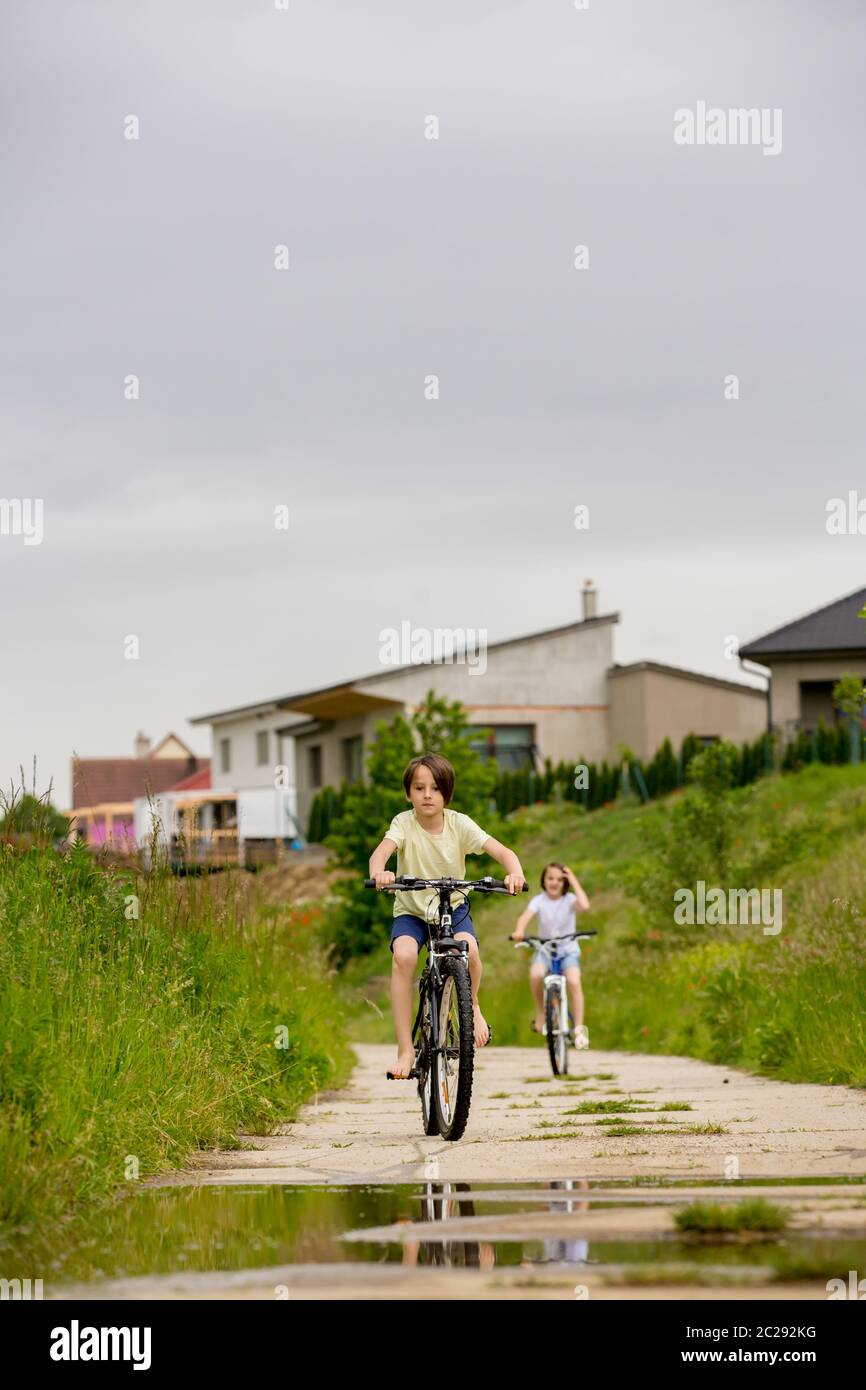 Child, boy, riding bike in muddy puddle, summer time on a rainy day ...