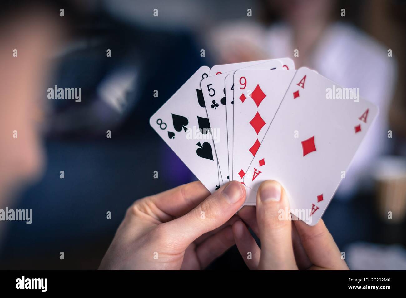Friends are playing cards together at home. Man is holding cards in her ...