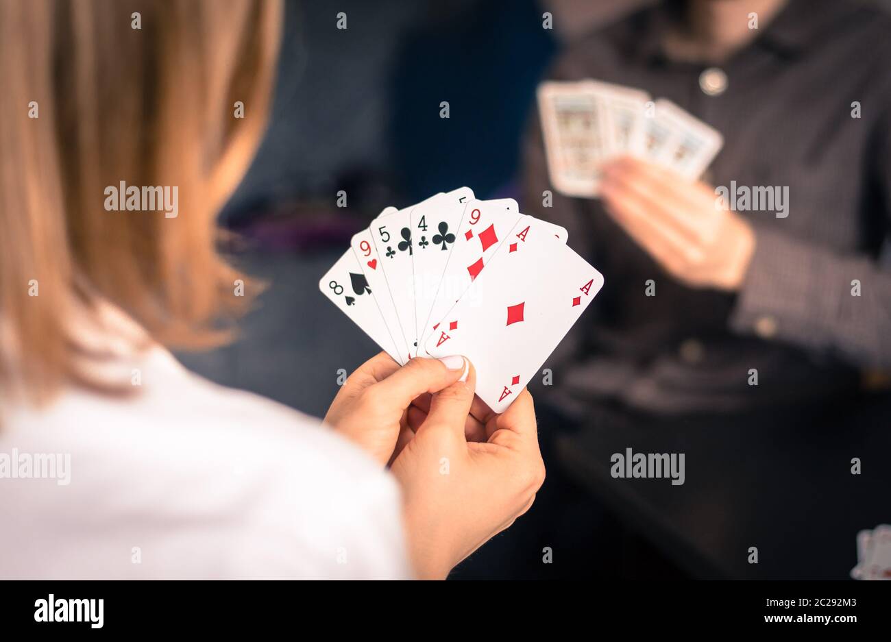 Friends are playing cards together at home. Woman is holding cards in ...