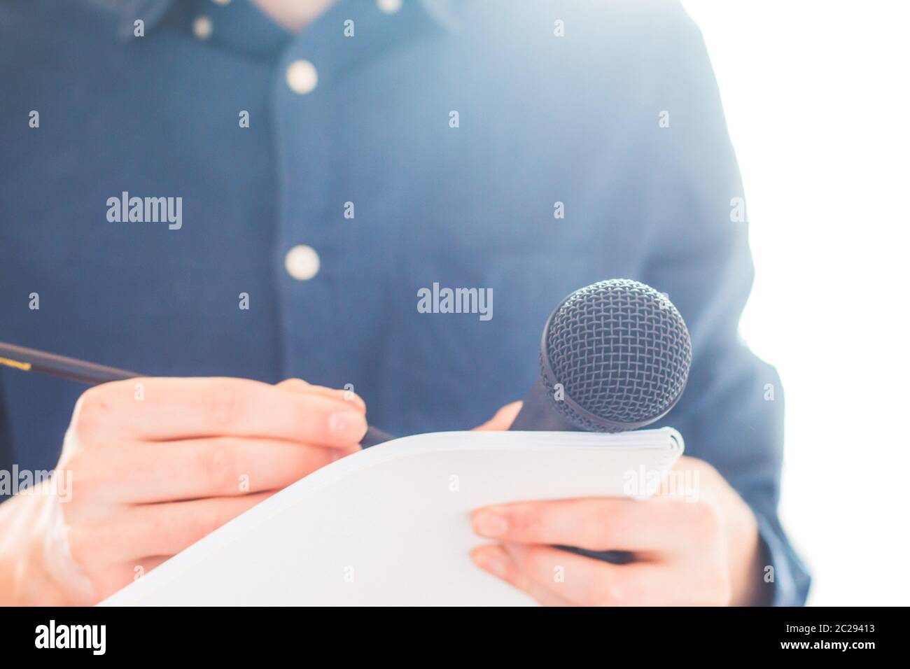 Male journalist at news conference, holding microphone and taking notes ...