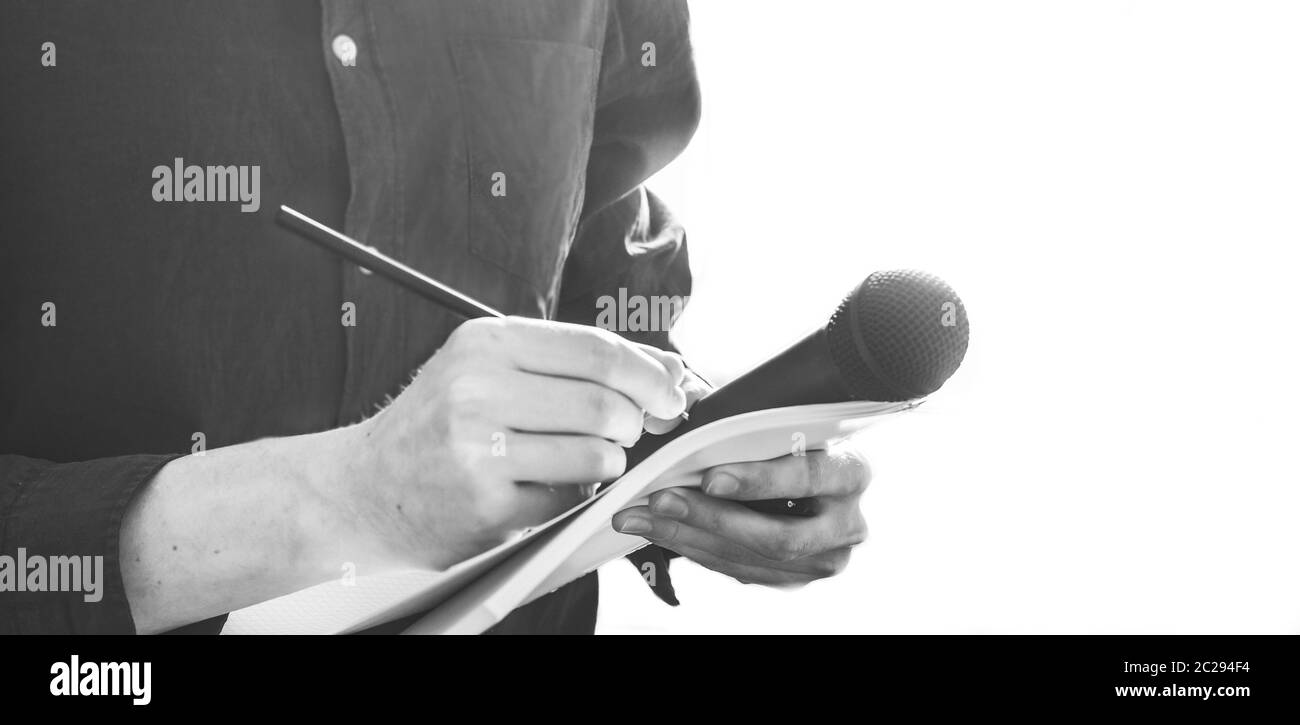 Male journalist at news conference, holding microphone and taking notes ...