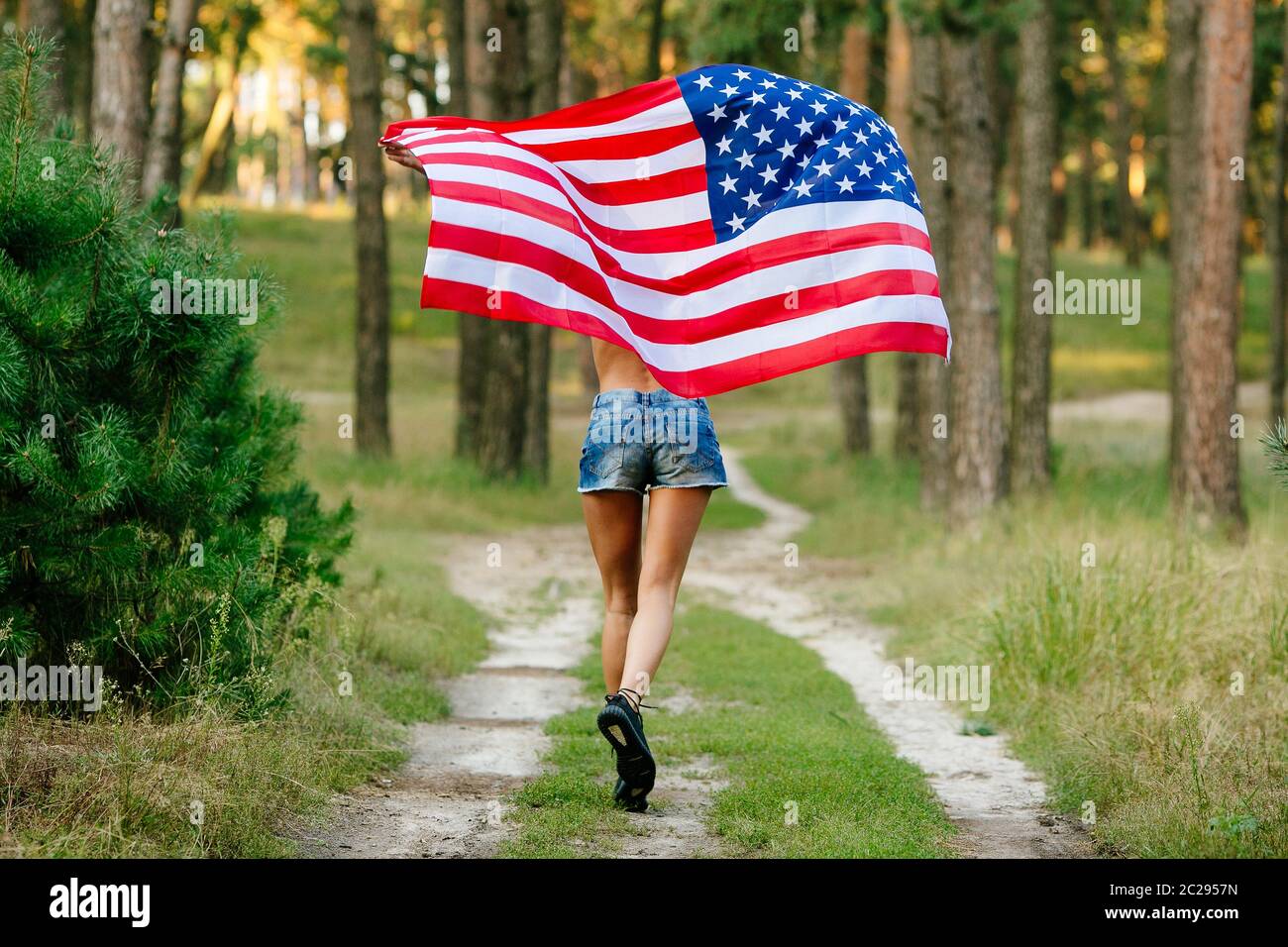 Girl in denim shorts running with American flag in hands Stock Photo ...