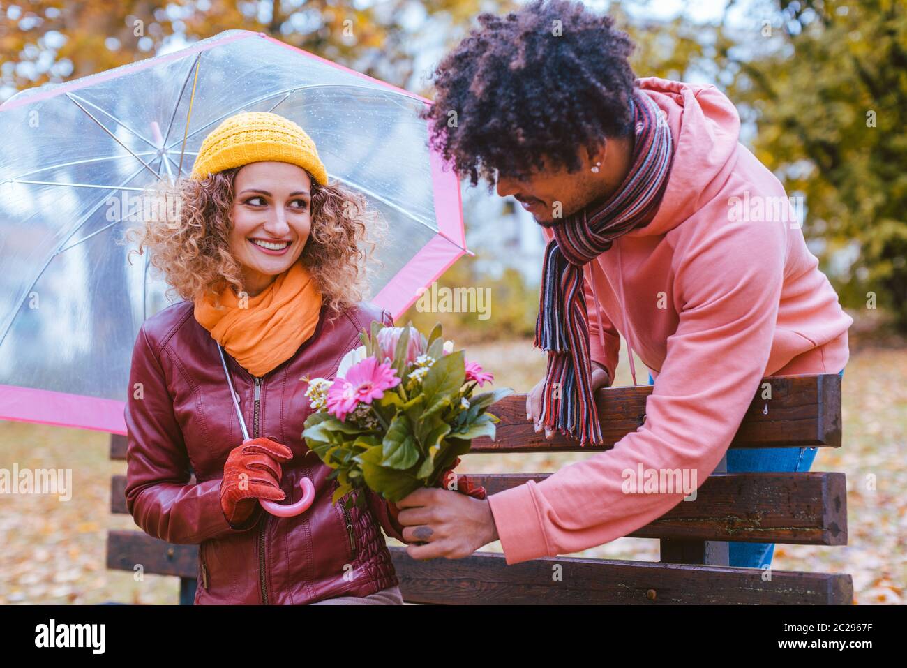 Man surprising his wife with a bouquet of flowers on a drizzly fall day ...