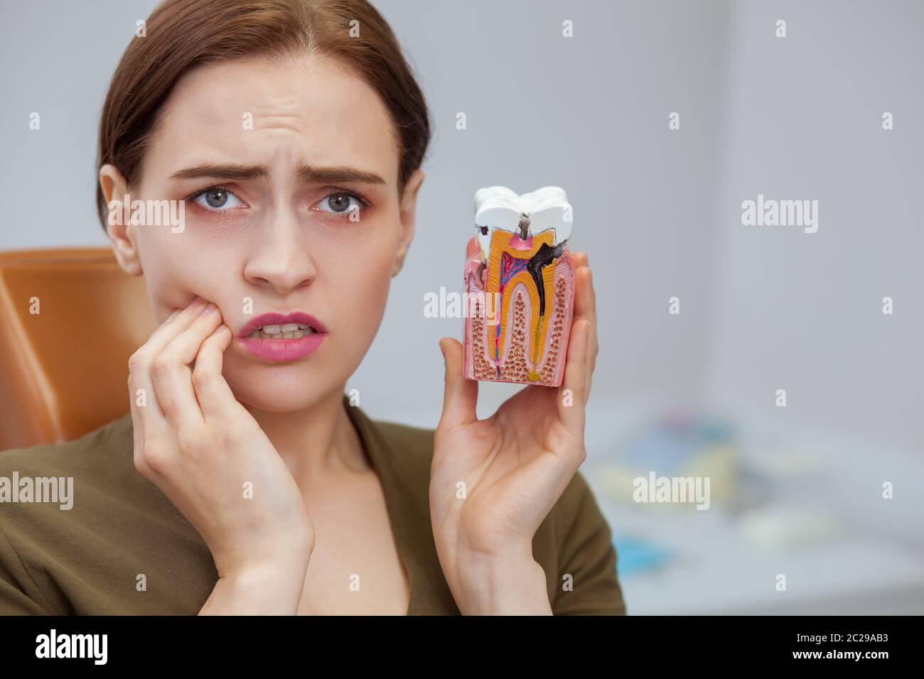 Young woman suffering from toothache, looking to the camera in despair ...