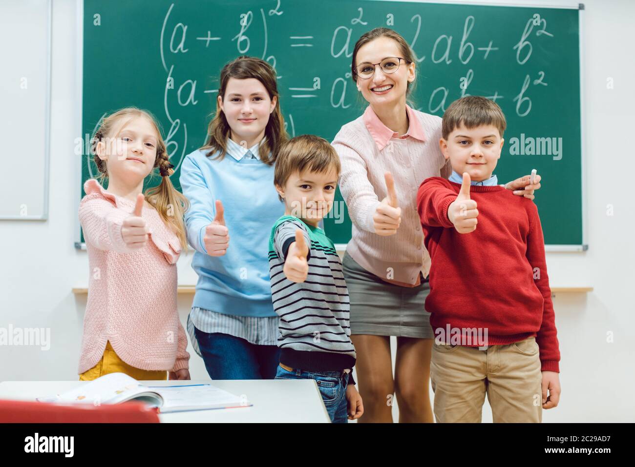 Pupils and teacher in class room of school showing thumbs-up having fun ...