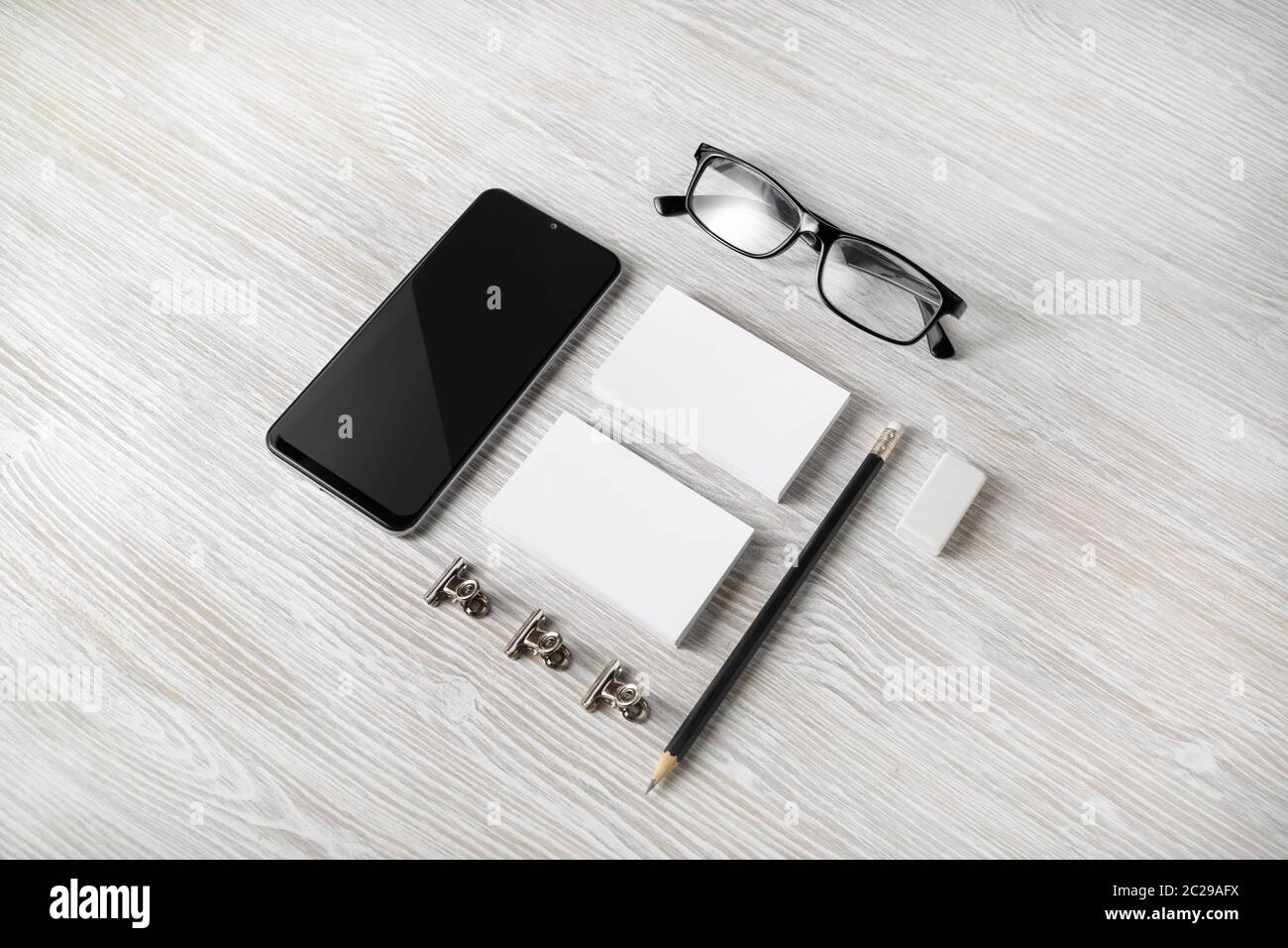 Blank stationery and smartphone on light wood table background ...