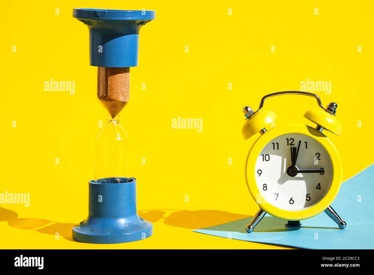 classic desktop clock, Hourglass colored background on yellow and blue ...