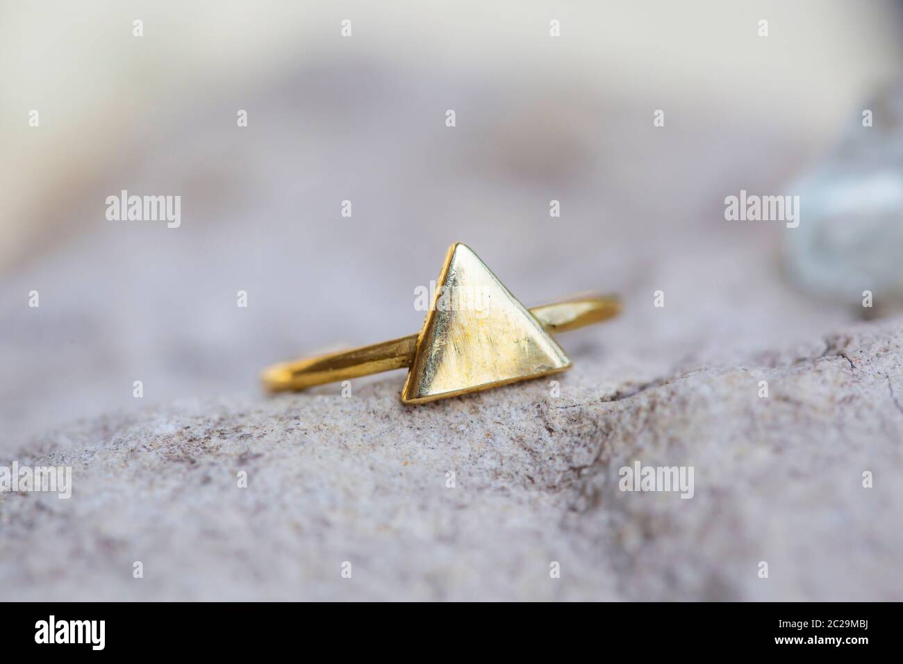 Golden metal triangle shape ring on natural neutral background Stock ...