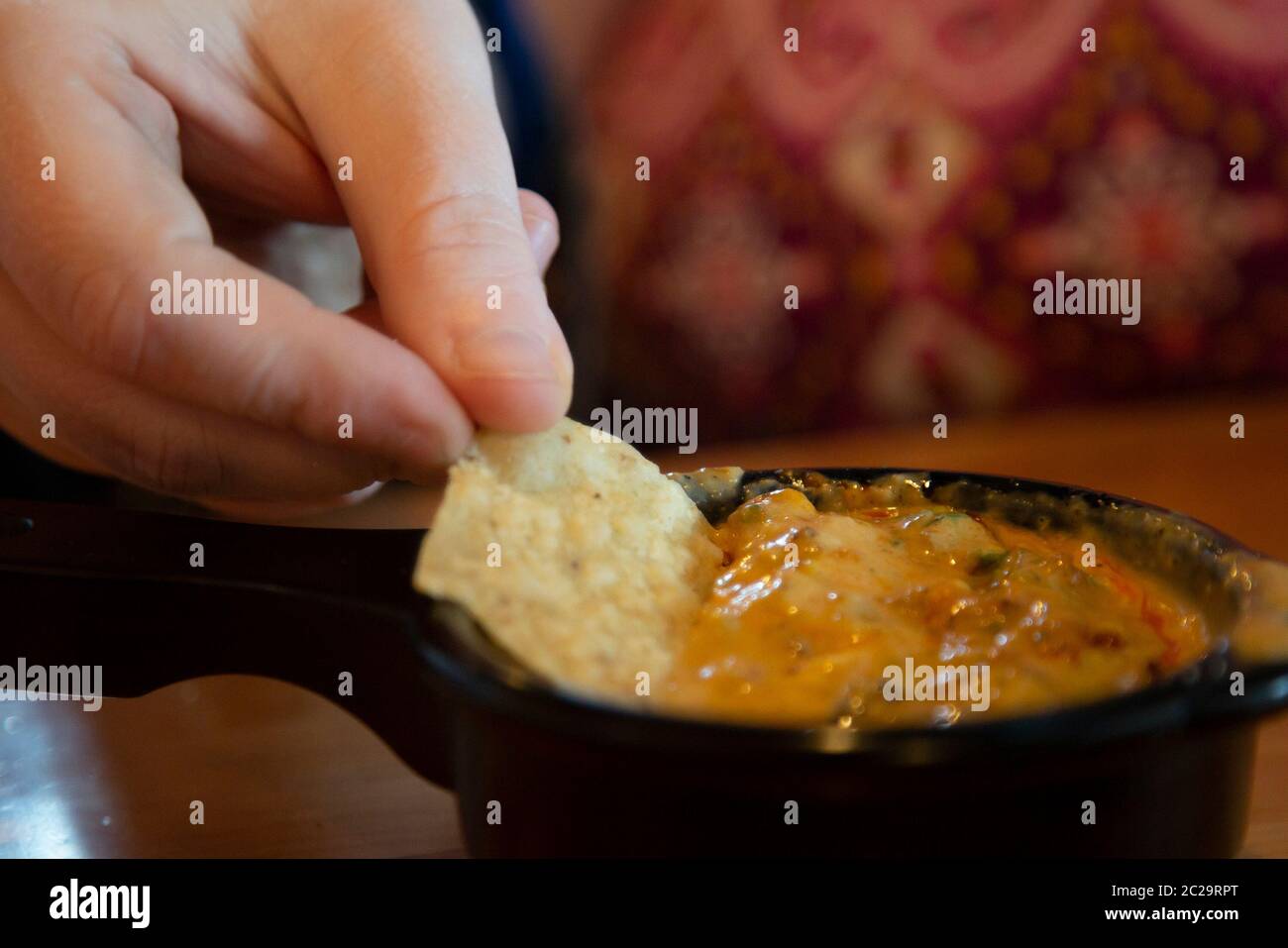 Woman dipping a chip into spicy queso dip Stock Photo - Alamy