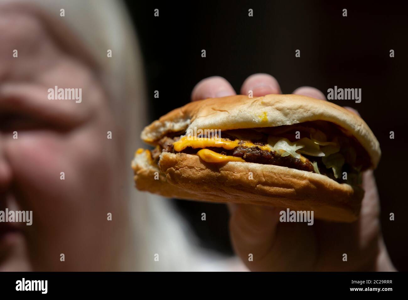 Albino woman eating a double meat cheese burger Stock Photo - Alamy