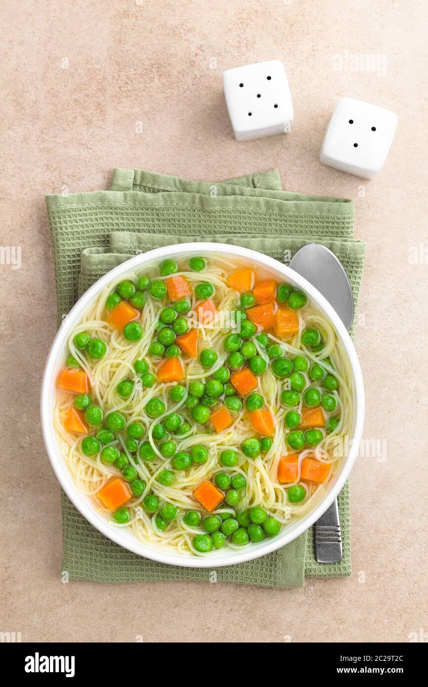Fresh homemade vegetable noodle soup with carrot, peas, onion and angel ...