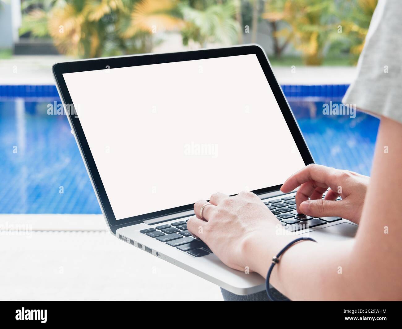 Young women working by the swimming pool. Female remote worker writing ...