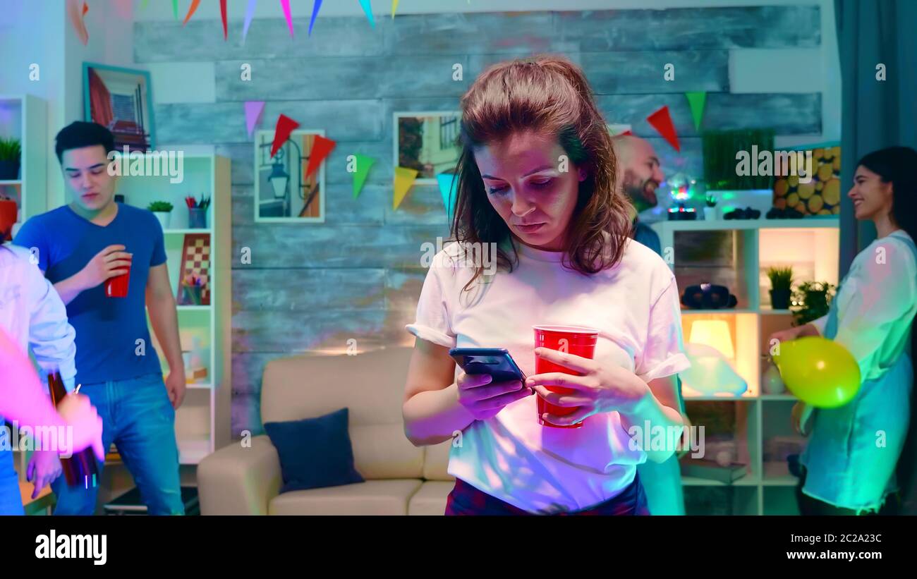 Zoom in shot of beautiful girl browsing on smartphone while her friends ...