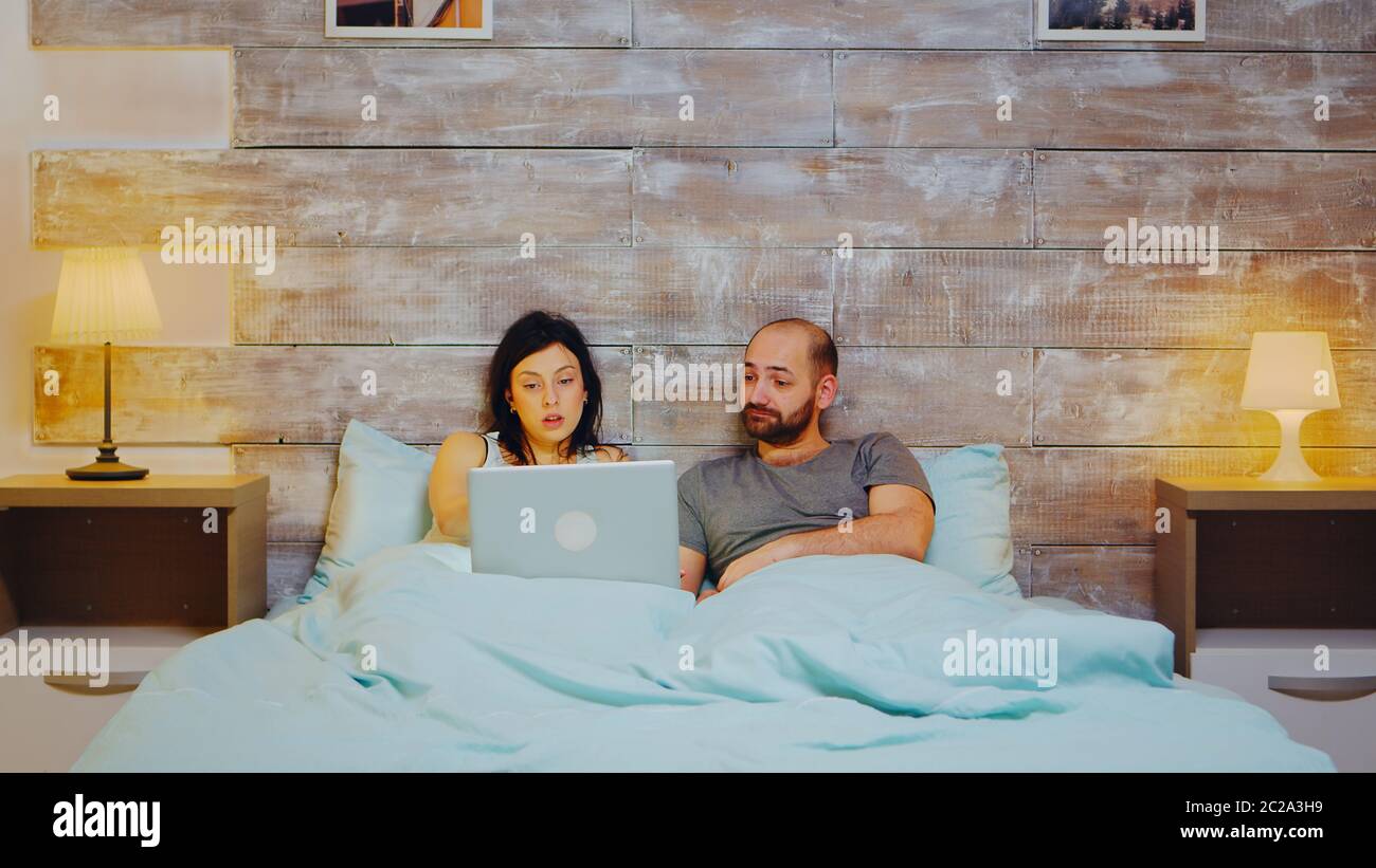 Young couple in pajamas doing shopping on laptop late at night Stock ...