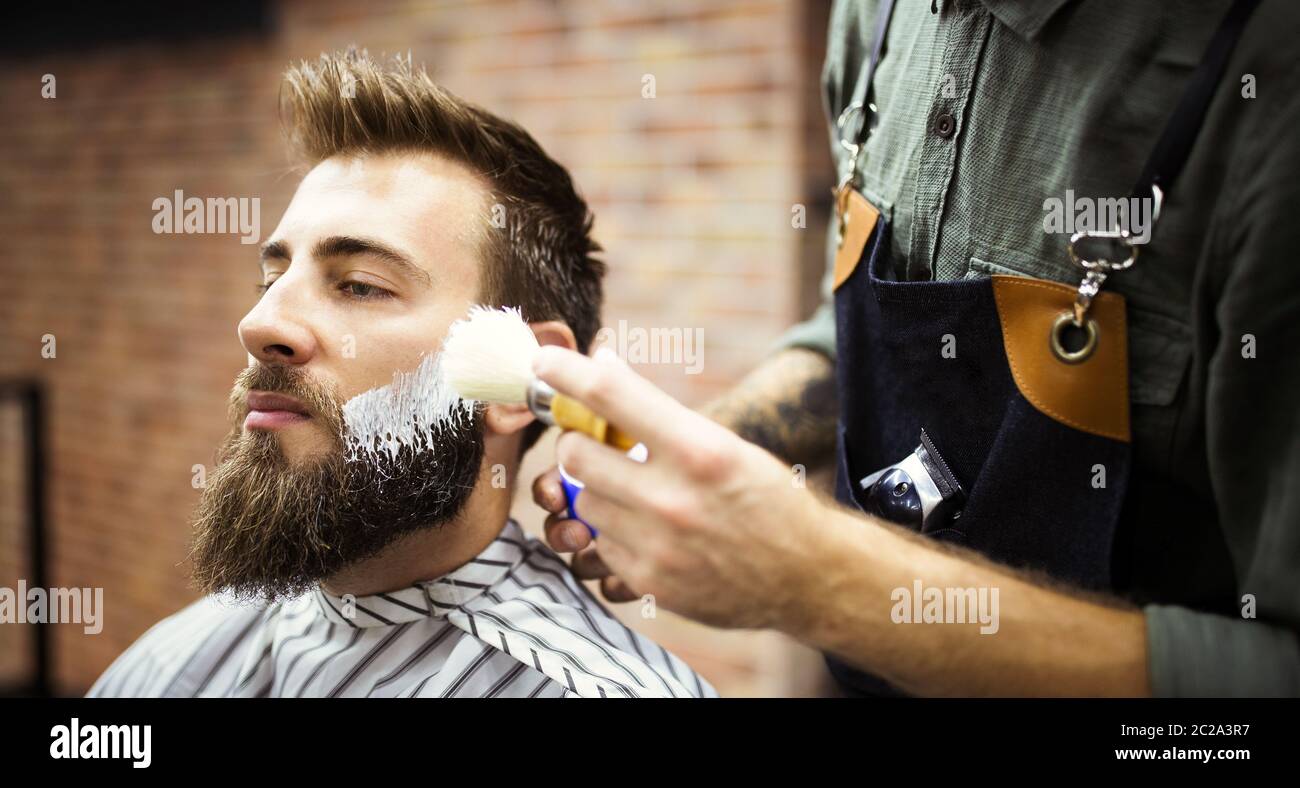Client during beard shaving in barber shop Stock Photo - Alamy