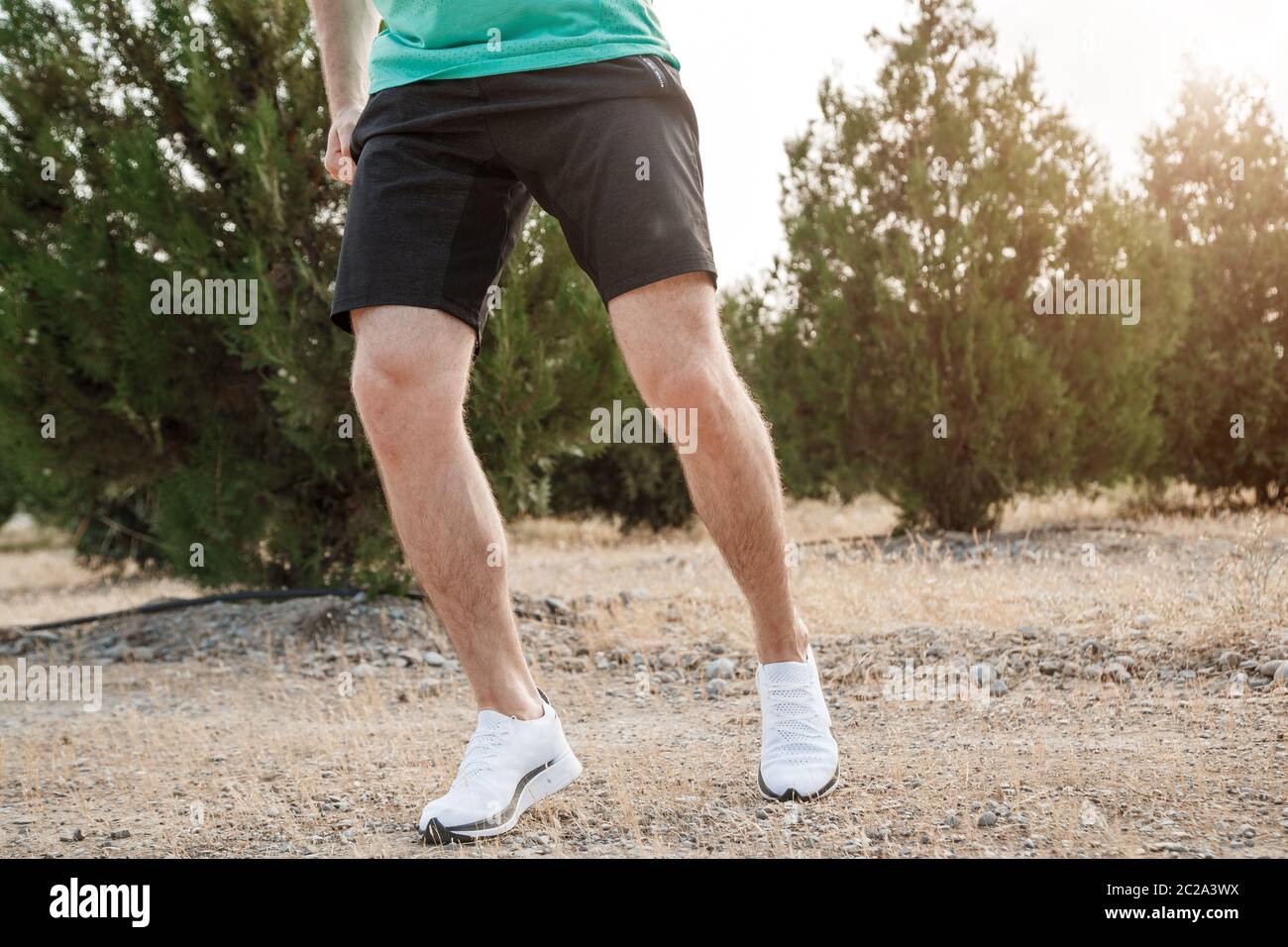 men's feet in white sneakers running over rough terrain. Cross country ...