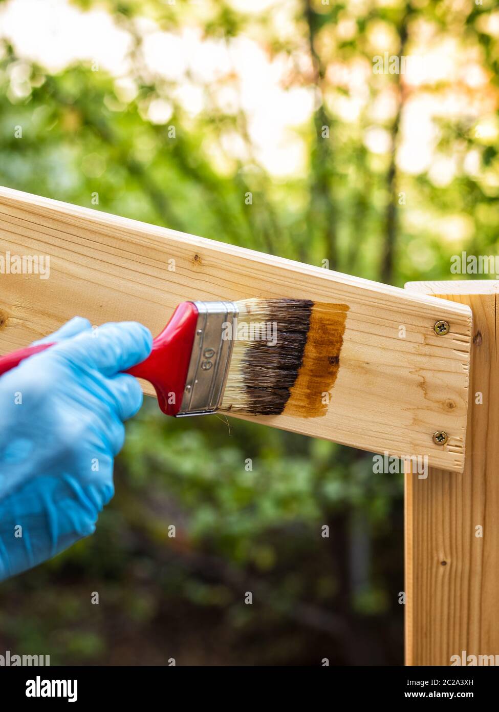 Adult craftsman carpenter with the brush painting the boards of a ...