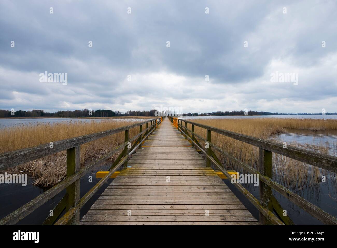 A perspective view down the wood pedestrian walking bridge over lake ...