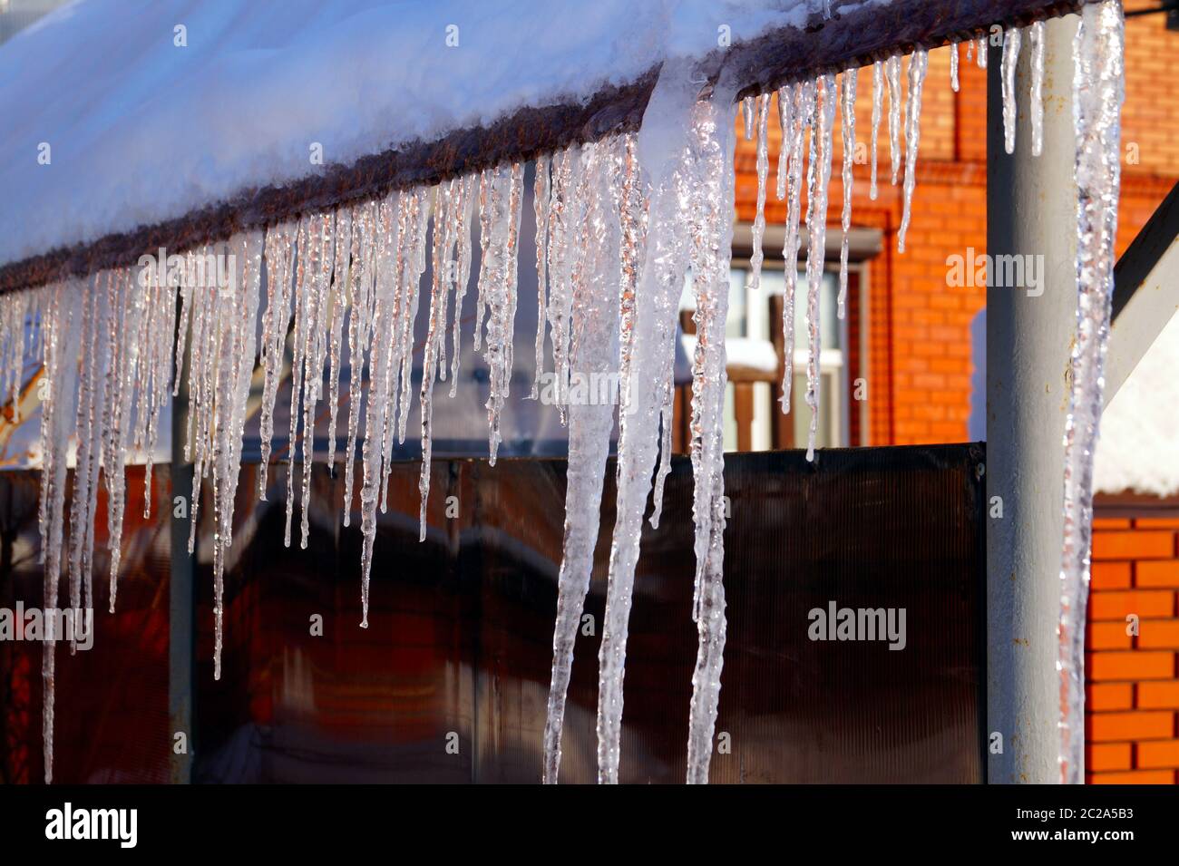 Many large and sharp icicles hang on the roof of the house Stock Photo ...