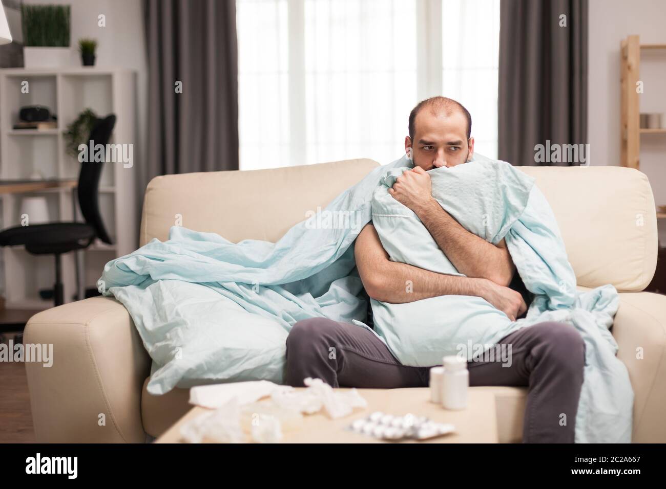 Sick man with chills wrapped in blacket during quarantine Stock Photo ...