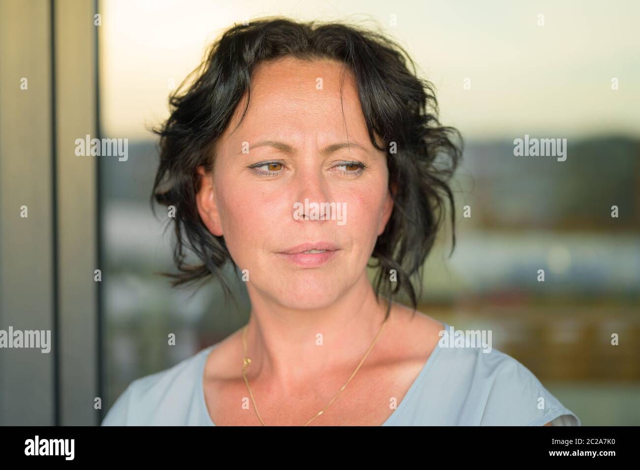 Candid portrait of a Hispanic woman squinting off to the side with a ...
