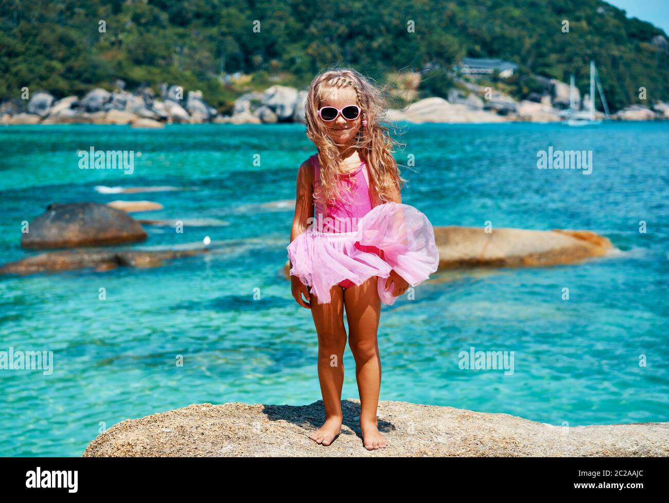 Cute little girl in sun glasses and pink dress posing on beautiful ...