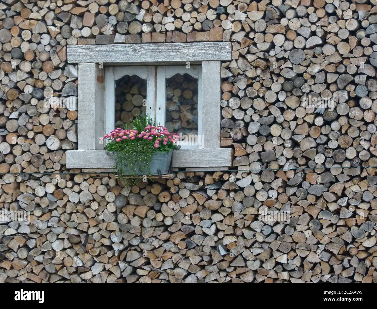 Funny window with floral decoration in a wall of firewood Stock Photo ...