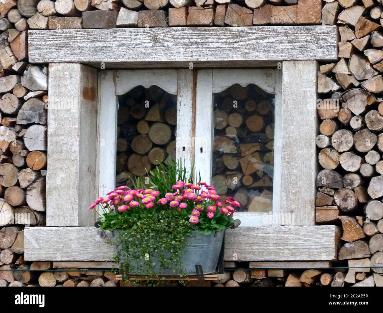 Funny window with floral decoration in a wall of firewood Stock Photo ...