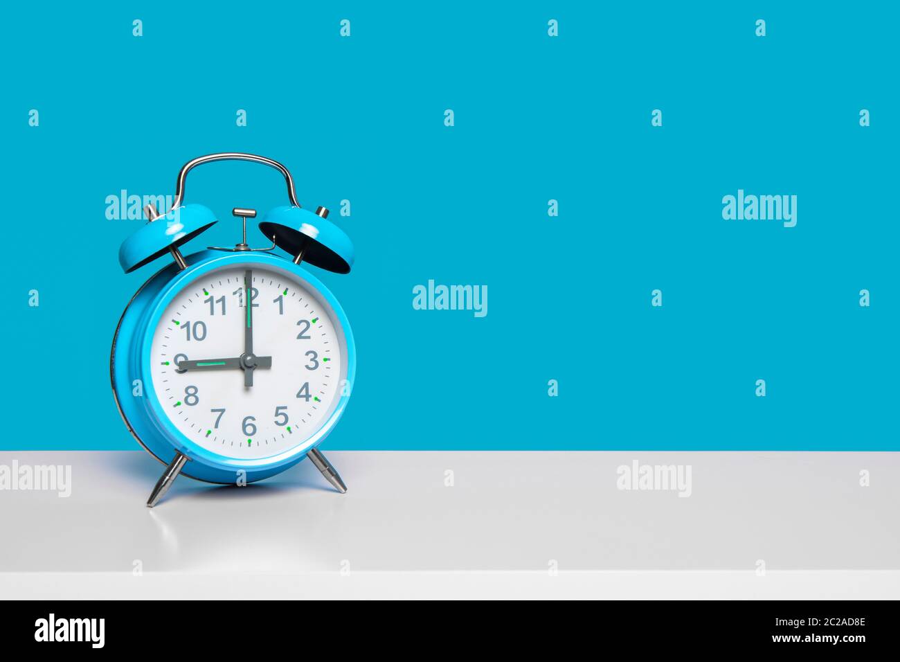 Blue vintage alarm clock at nine o’ clock on a blue background with ...