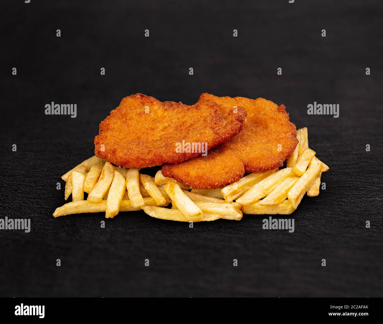 Breaded German weiner schnitzel with fried potatoes on dark background ...