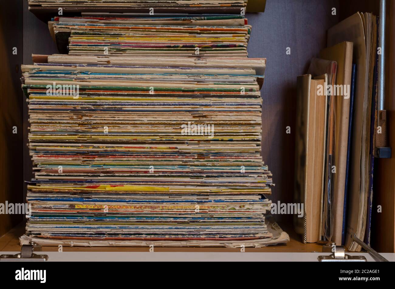 A stack of shabby old magazines and comics on a cabinet shelf ...