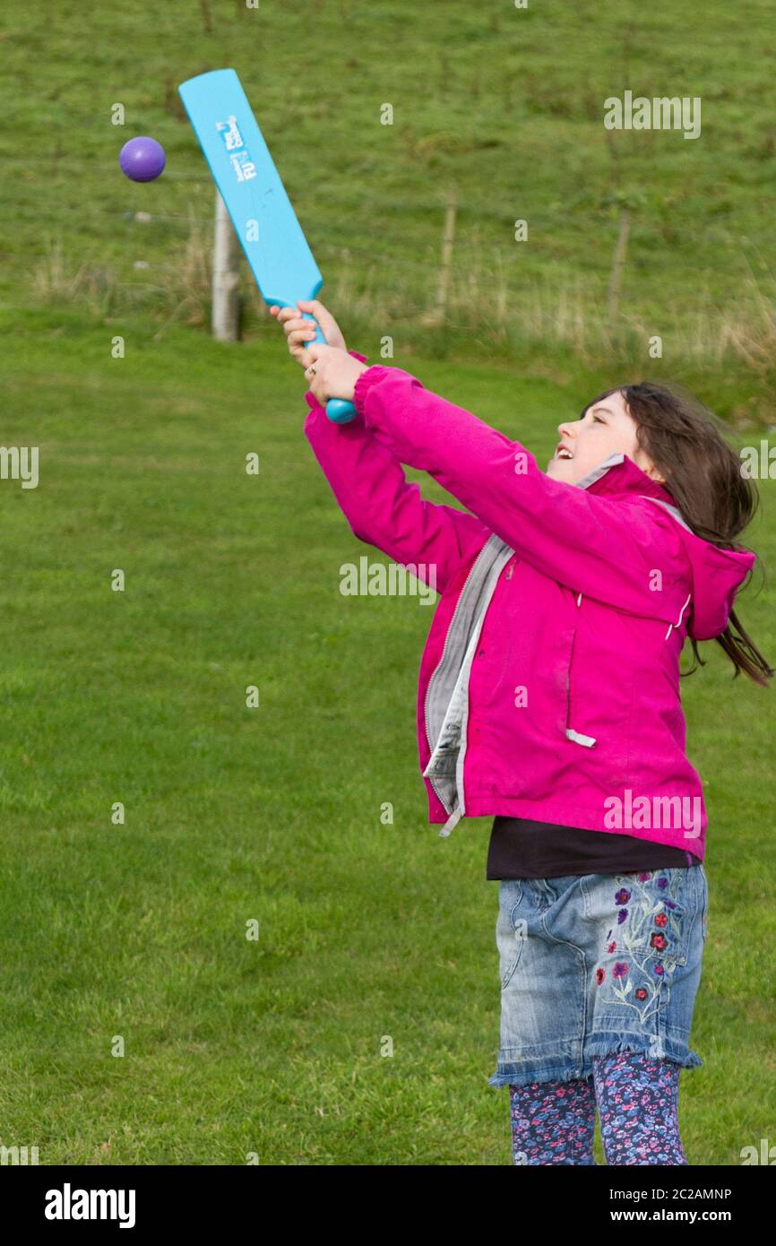 Young girl batting a ball in garden Stock Photo - Alamy