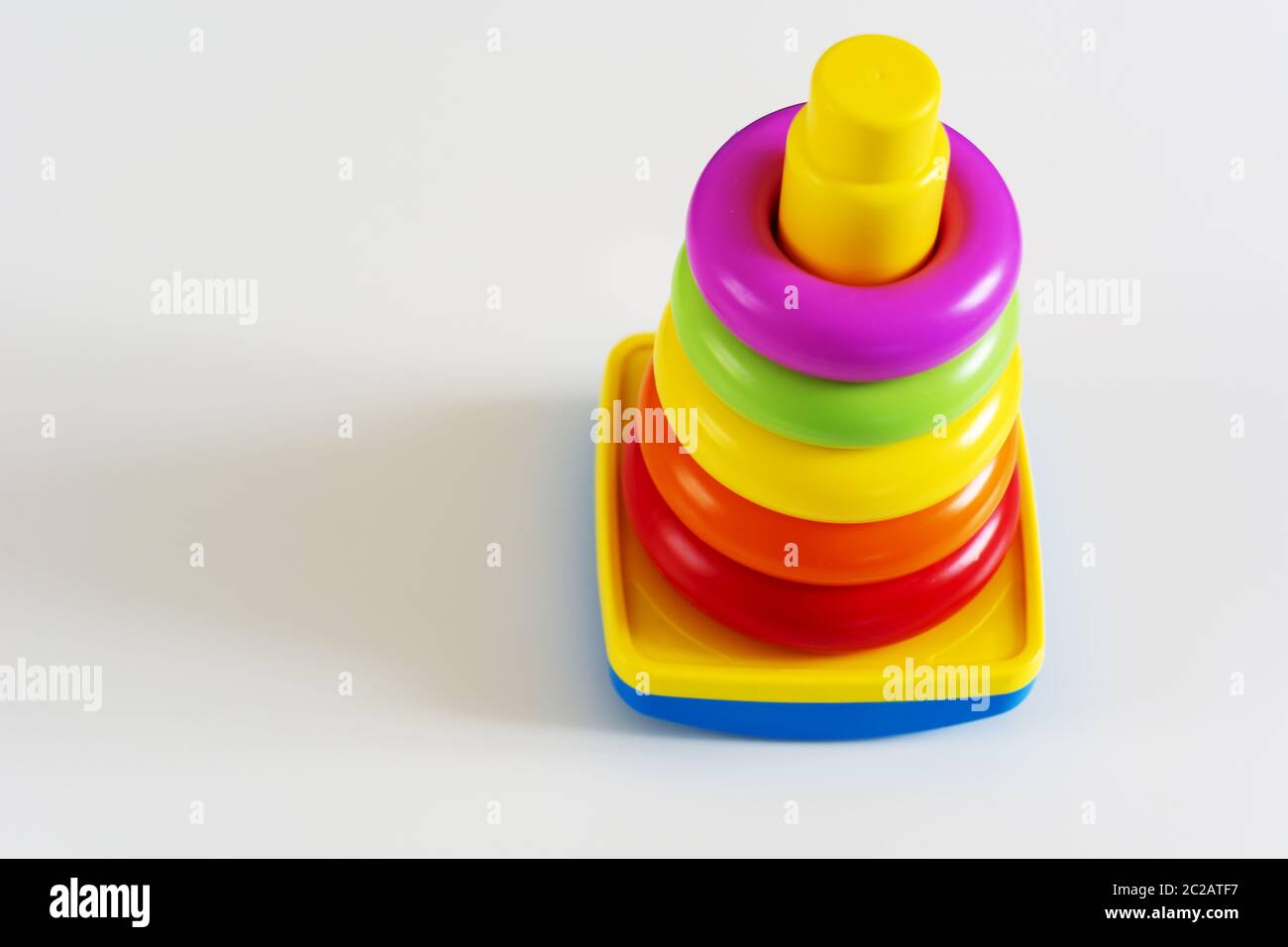 Plastic rings of various colors are stacked in a yellow plastic tower ...