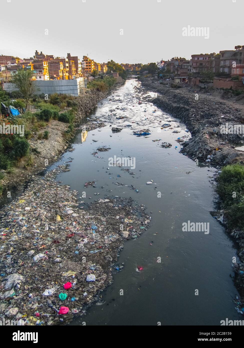 Polluted river runs through city. waste is discarded river bank. lack ...