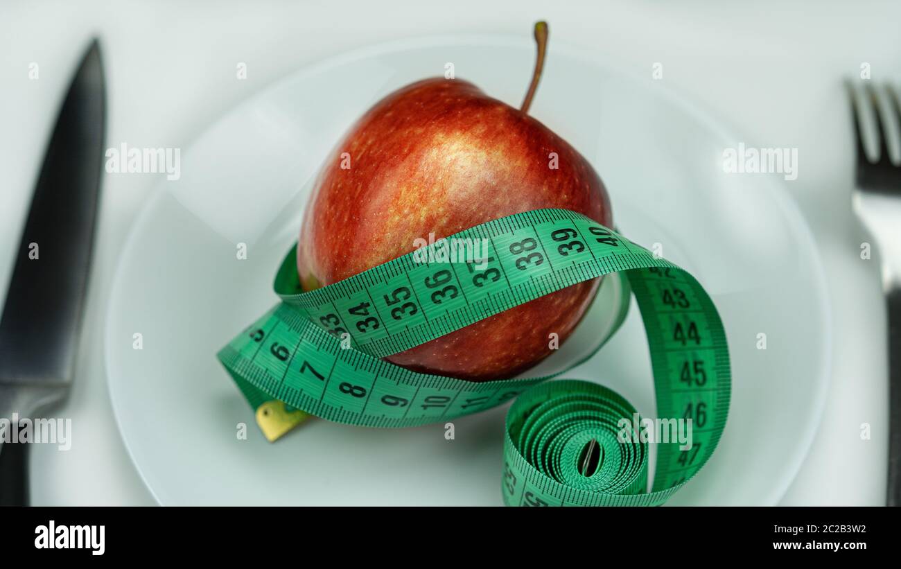An Apple, a tape measure, nuts, and placed on a white background remind ...