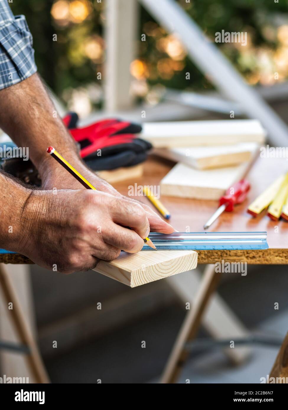 Adult craftsman carpenter with pencil and ruler tracing the cutting ...