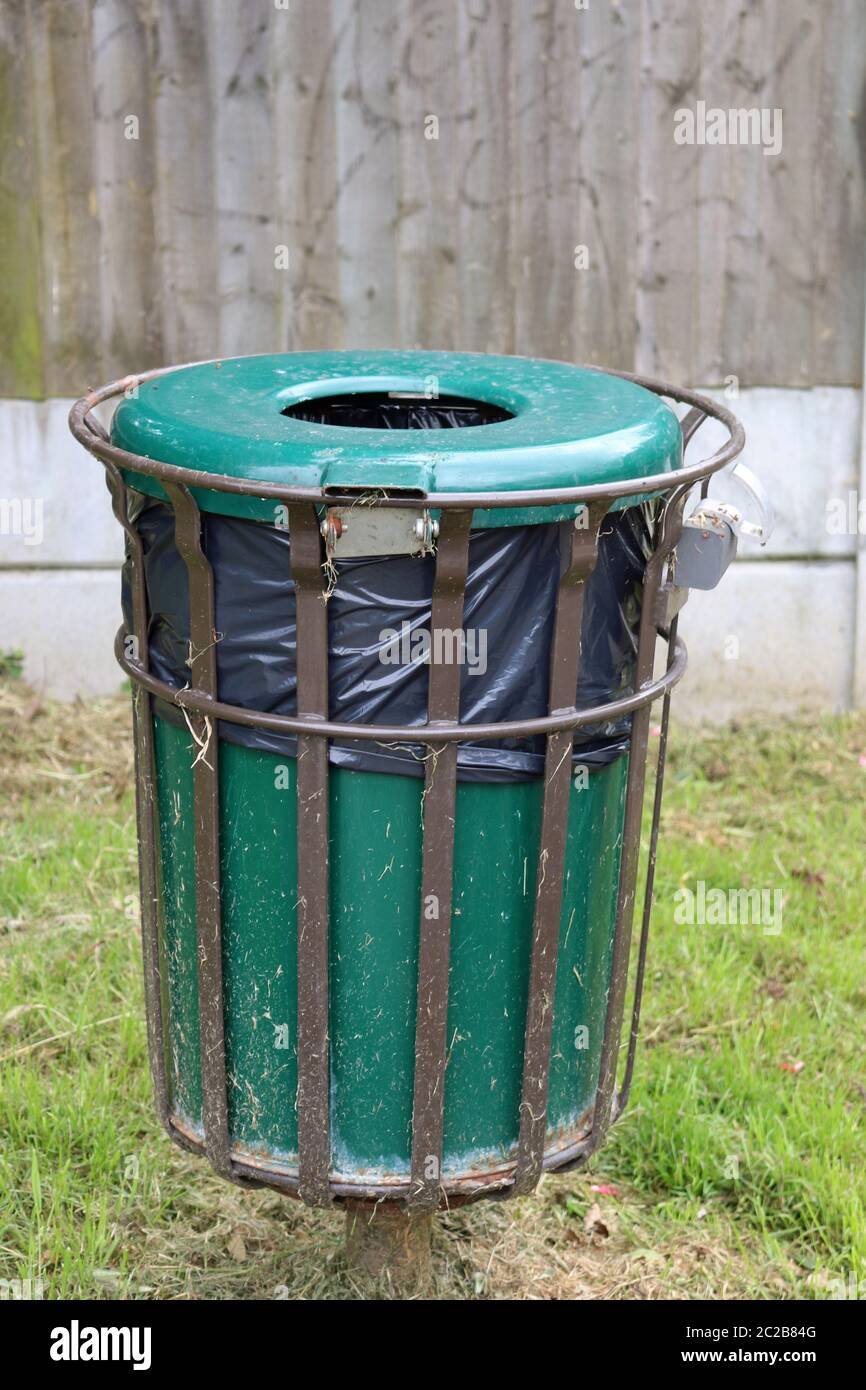 Green litter bin in a metal frame containing a black plastic bin liner ...