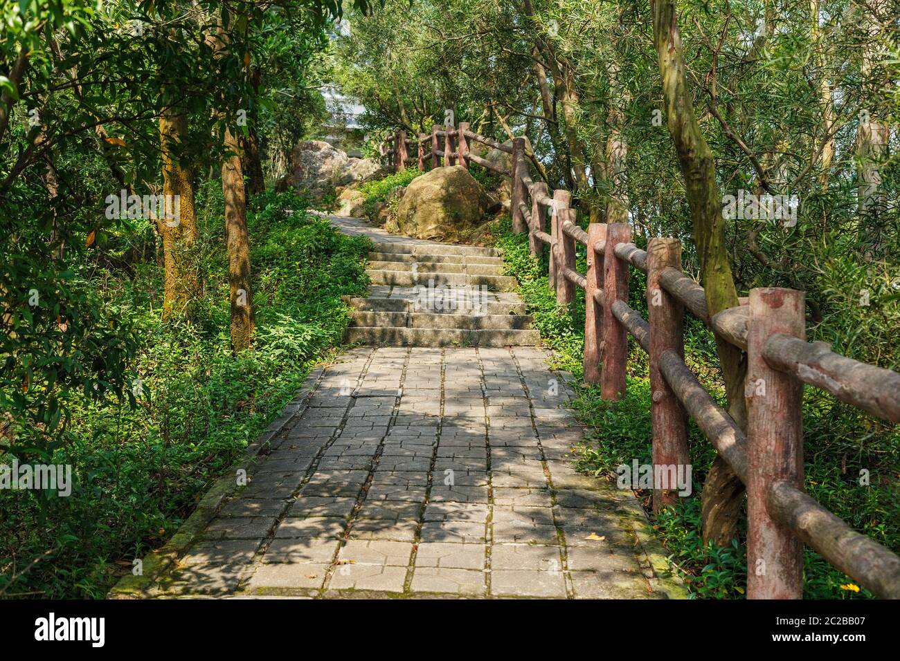 Concrete tile walkway with log railing in a mountain park, Shenzhen ...
