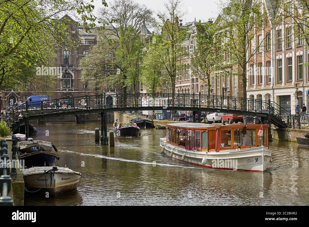 Tourist boat under one of the many bridges over a canal in Amsterdam ...
